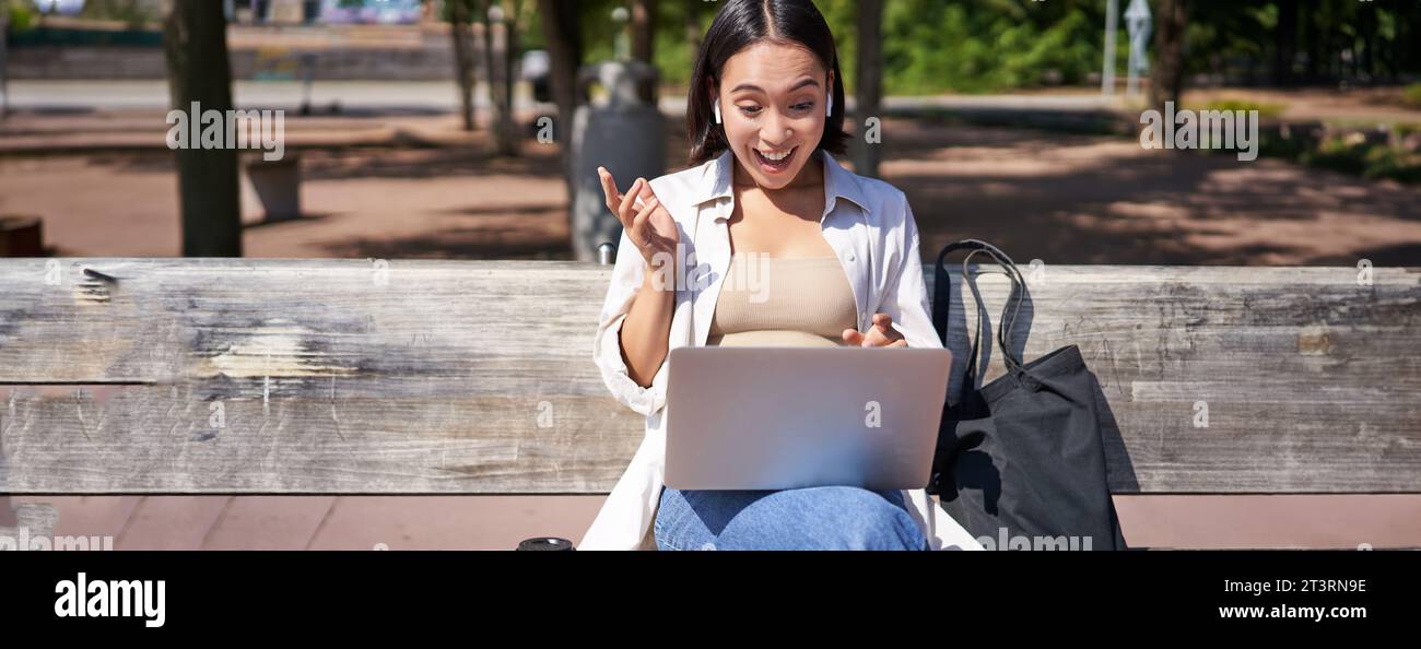 Happy asian girl chatting, having video call on laptop, sitting on ...