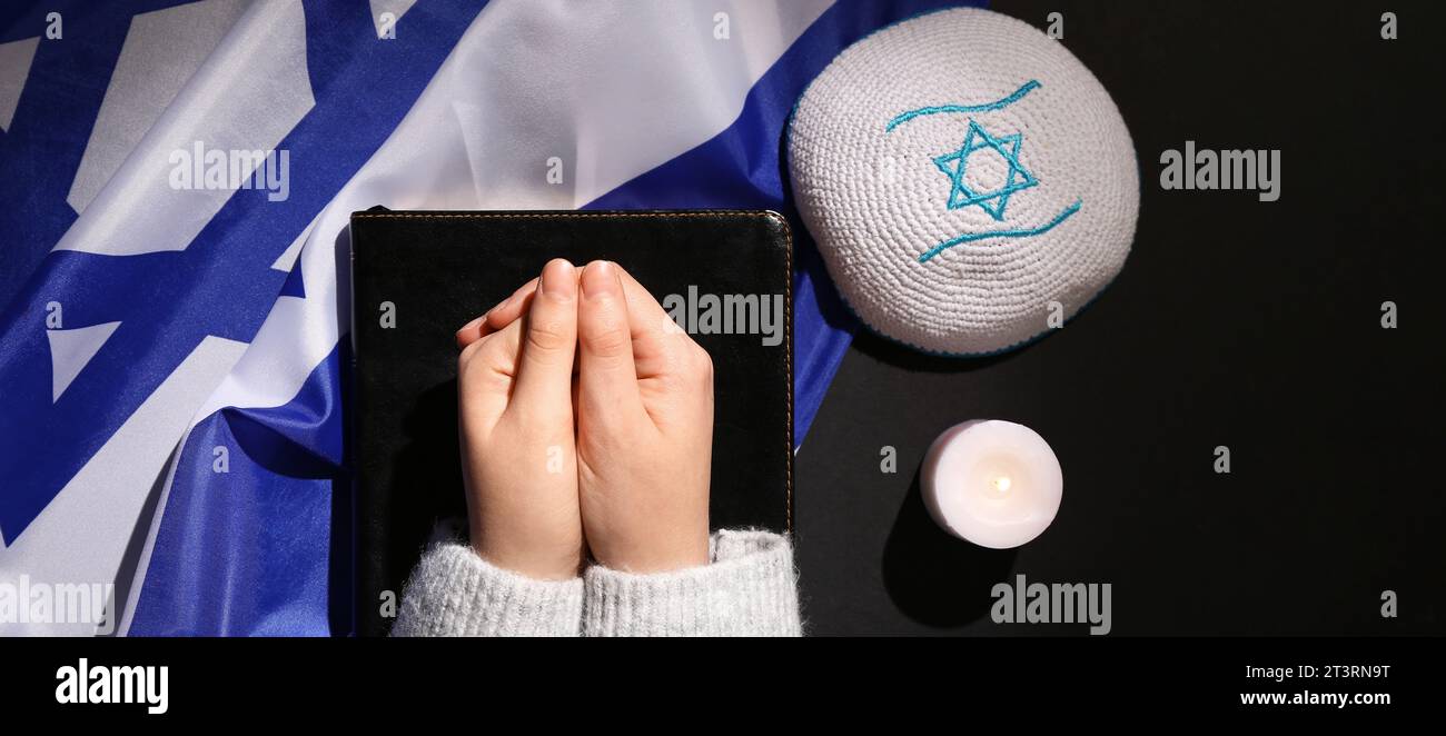 Praying woman with Torah, Jewish hat, burning candle and flag on dark ...