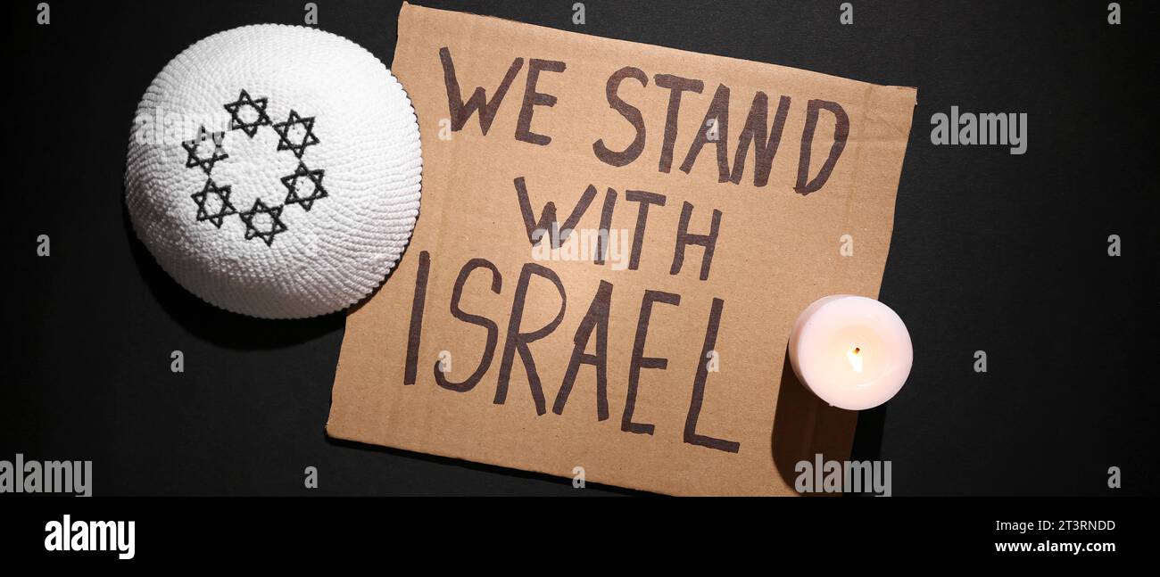 Cardboard with text WE STAND WITH ISRAEL, Jewish hat and burning candle ...