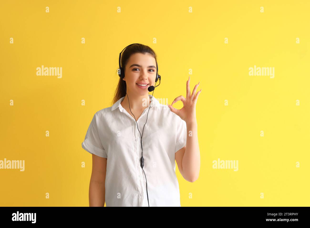 Female technical support agent showing OK on yellow background Stock ...