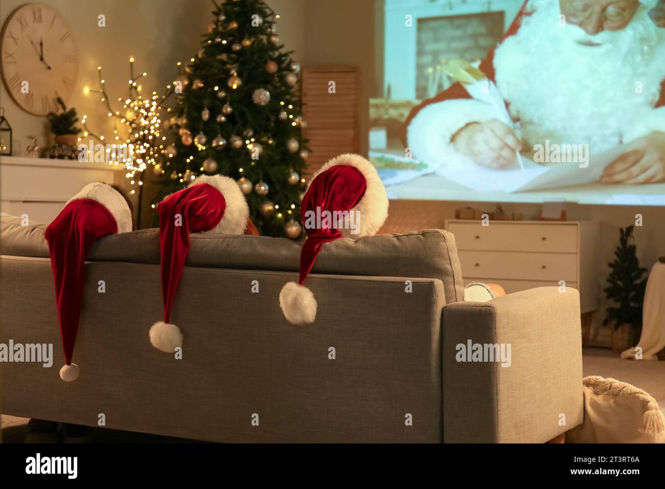 Young women in Santa hats watching Christmas movie on projector screen ...