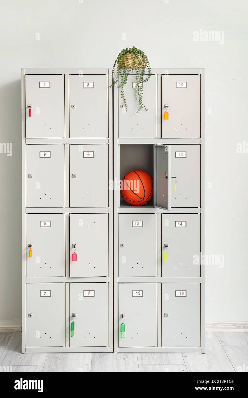 Modern locker with ball and plant near light wall Stock Photo - Alamy