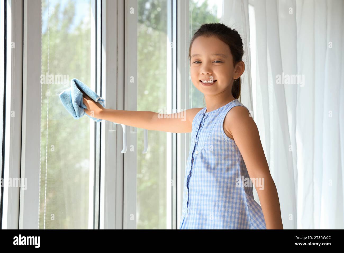Cute little girl cleaning window at home Stock Photo - Alamy