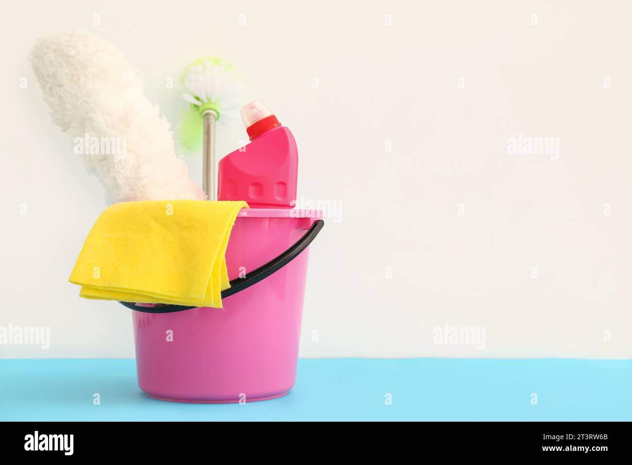 Bucket with cleaning supplies on blue table against white background ...