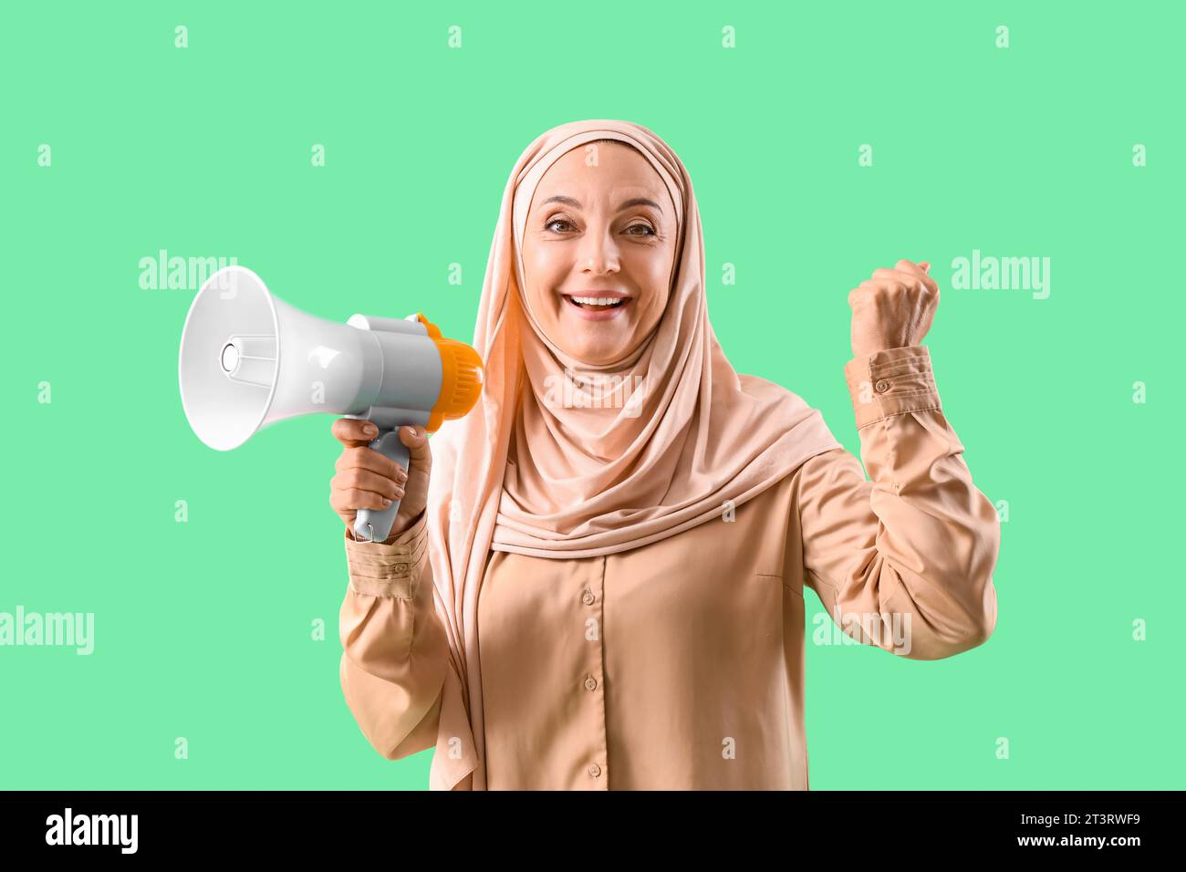 Mature Muslim woman shouting into megaphone on green background Stock ...