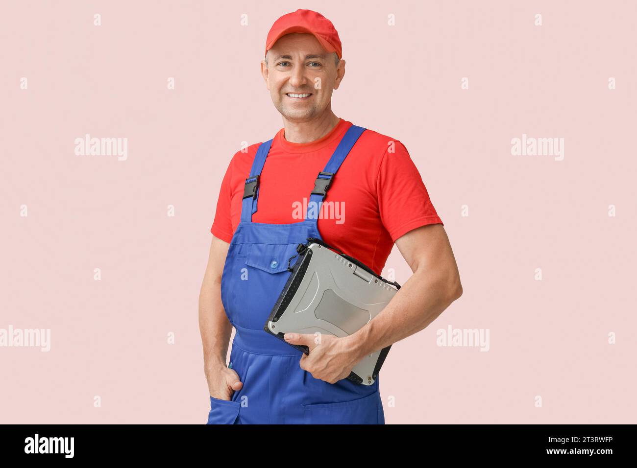Portrait of male mechanic with old laptop on pink background Stock ...