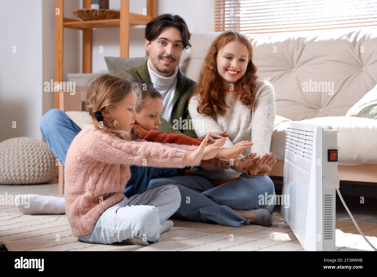 Frozen family warming near radiator at home Stock Photo - Alamy