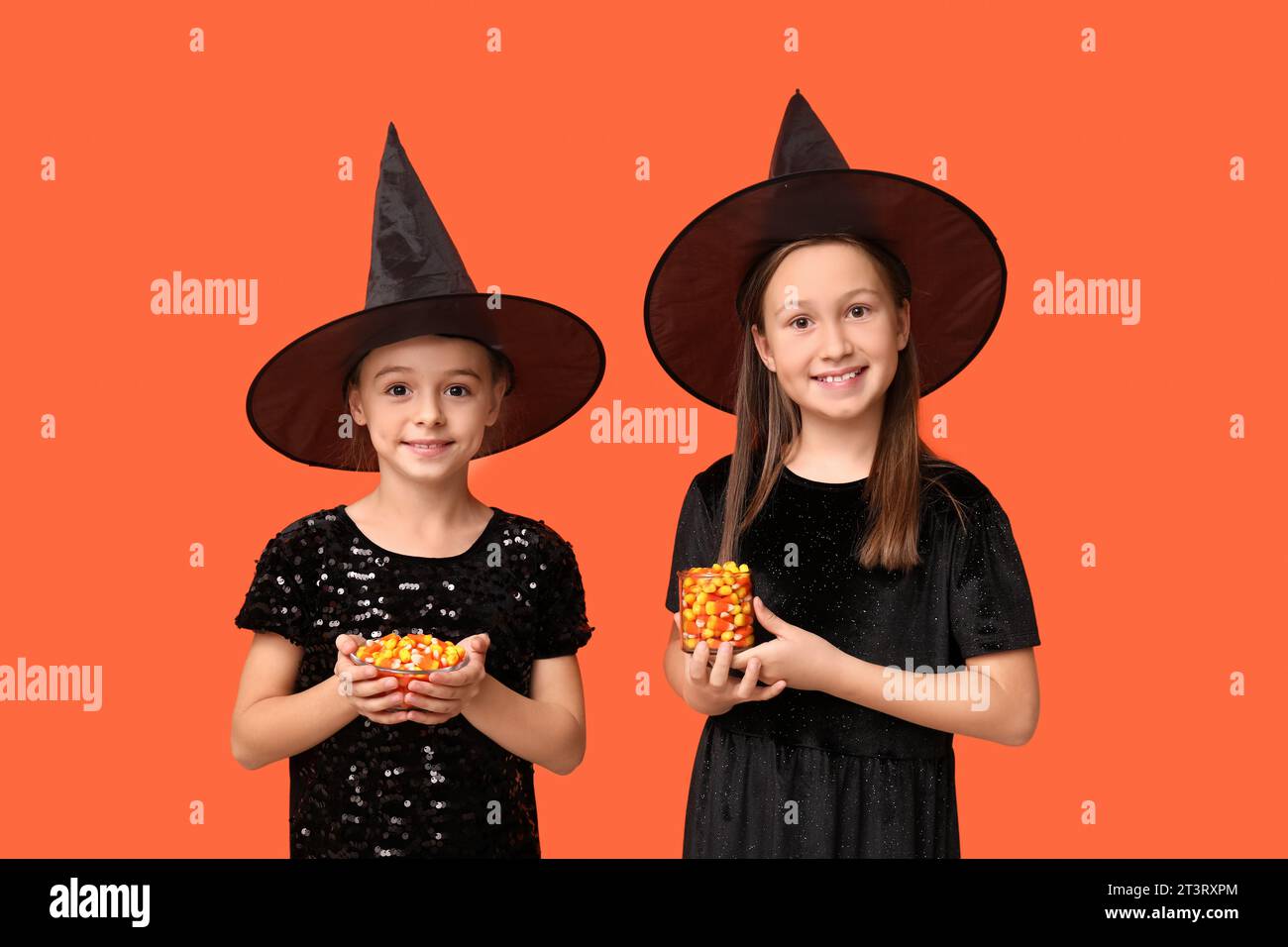Cute little girls dressed for Halloween as witches with tasty candies ...