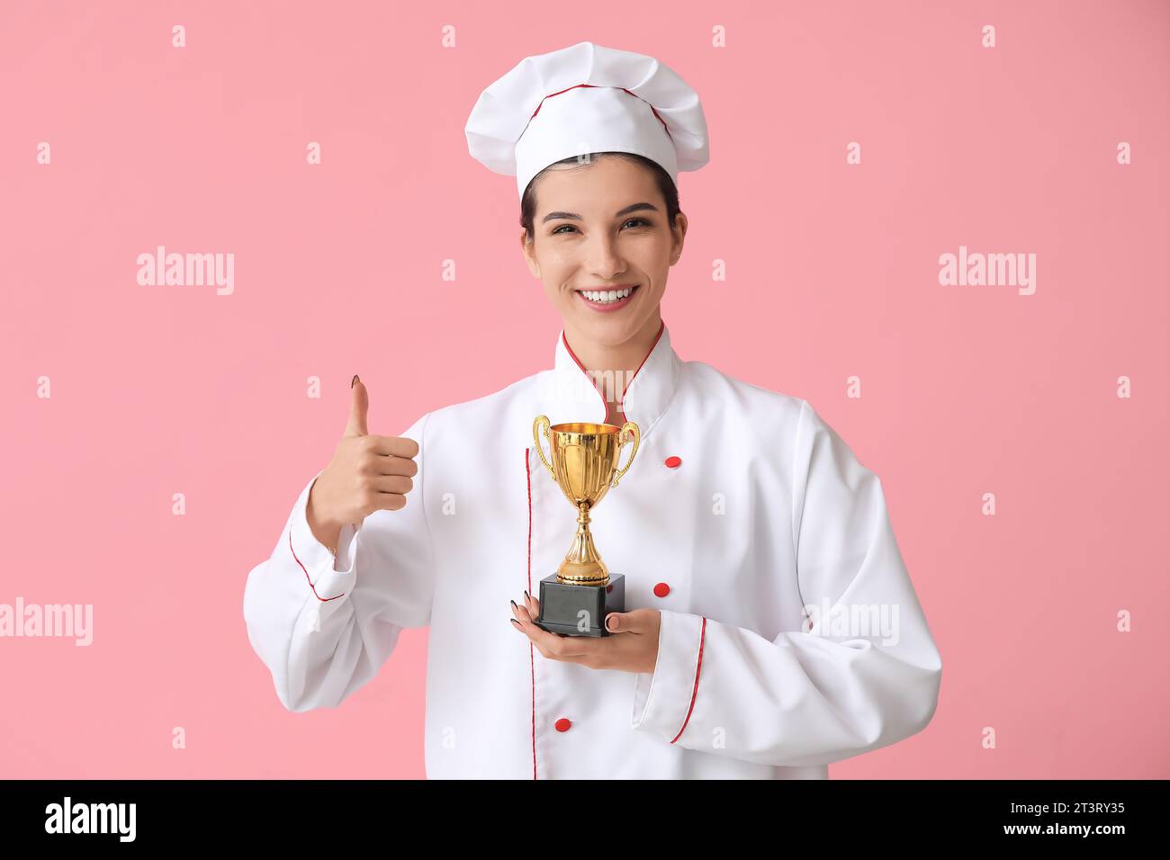 Female chef with gold cup showing thumb-up on pink background Stock ...