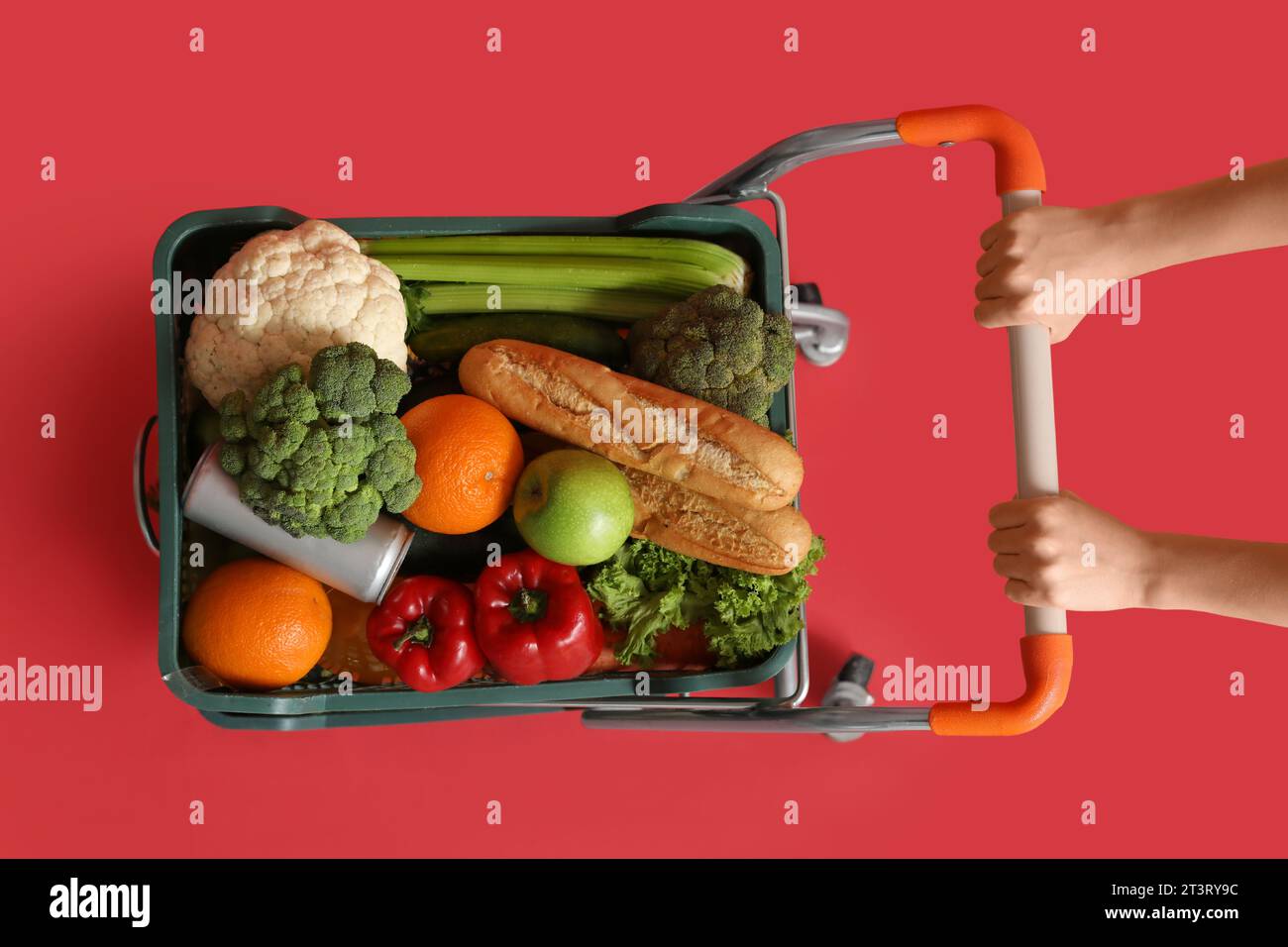 Woman pushing shopping cart full of food on red background Stock Photo ...
