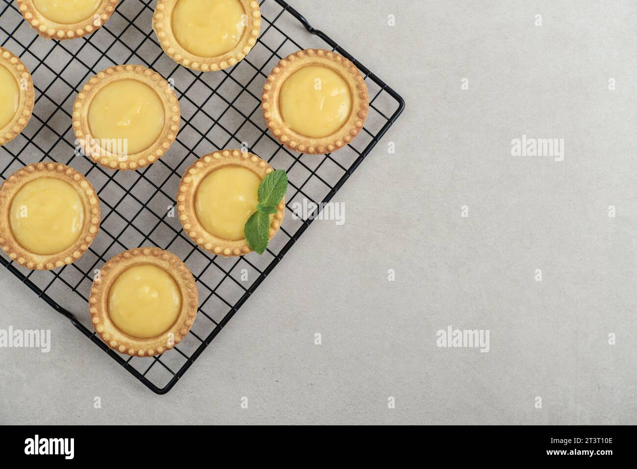 Mini tarts with lemon and custard filling on black metal cooling rack ...