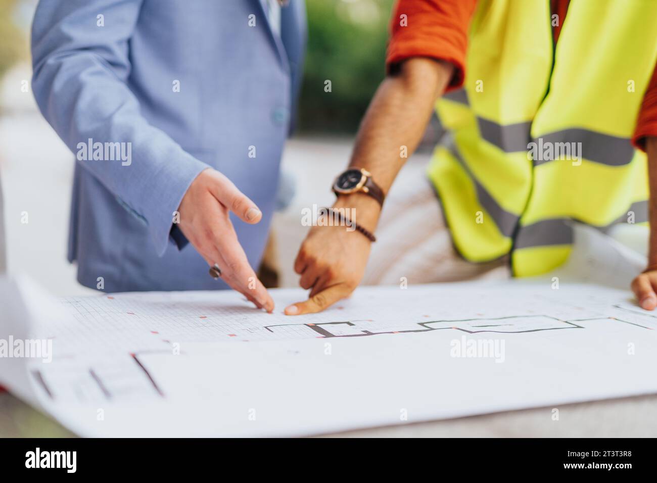 Architects, engineers, and designers collaborate outdoors, reviewing ...