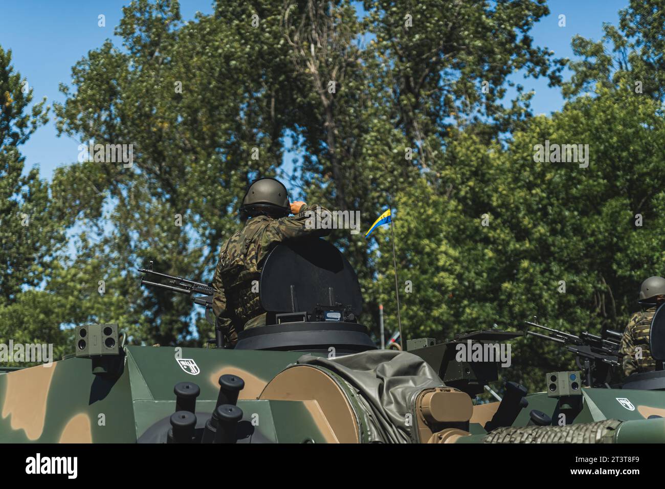 Back view of a fully armed soldier peeking out of the tank entrance ...