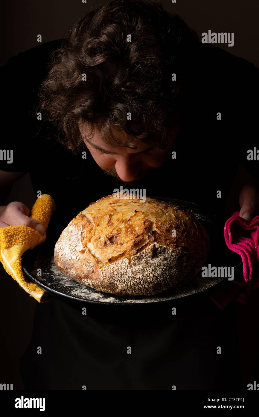 Attractive young Caucasian chef posing with white sourdough bread. The ...