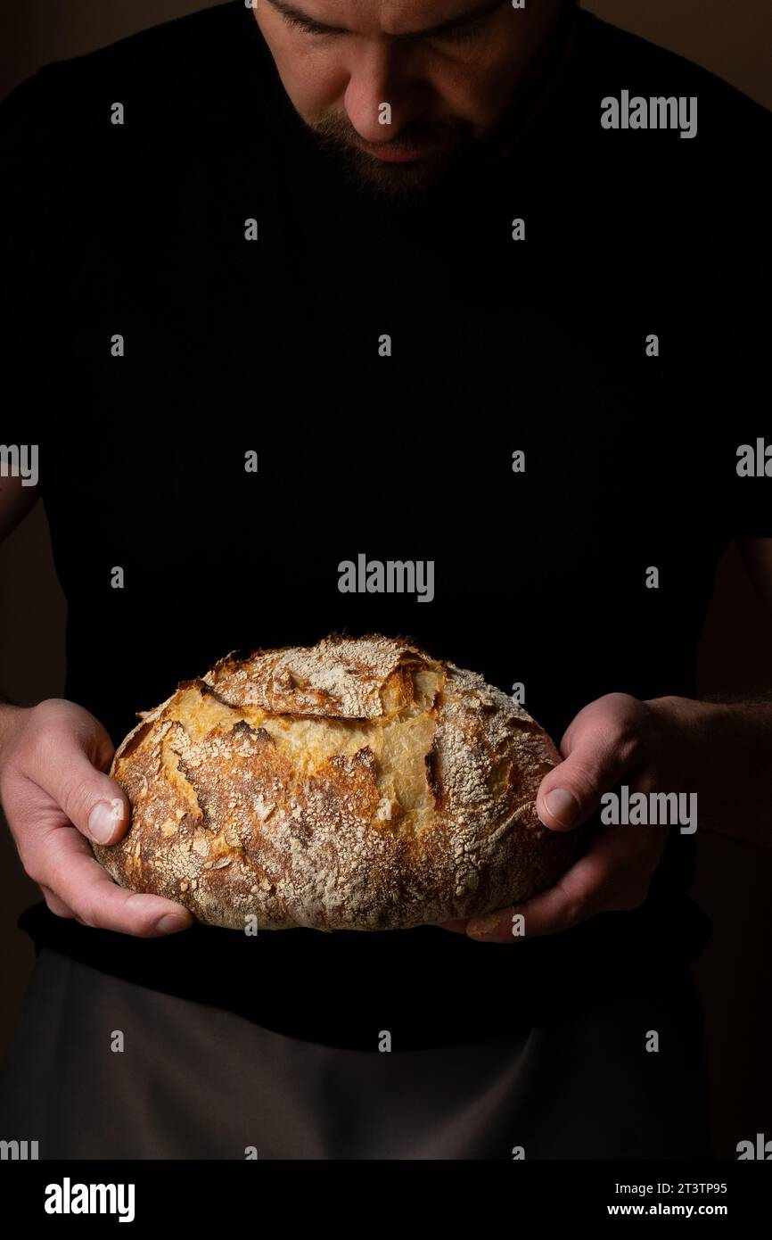 Attractive young Caucasian chef posing with white sourdough bread. The ...