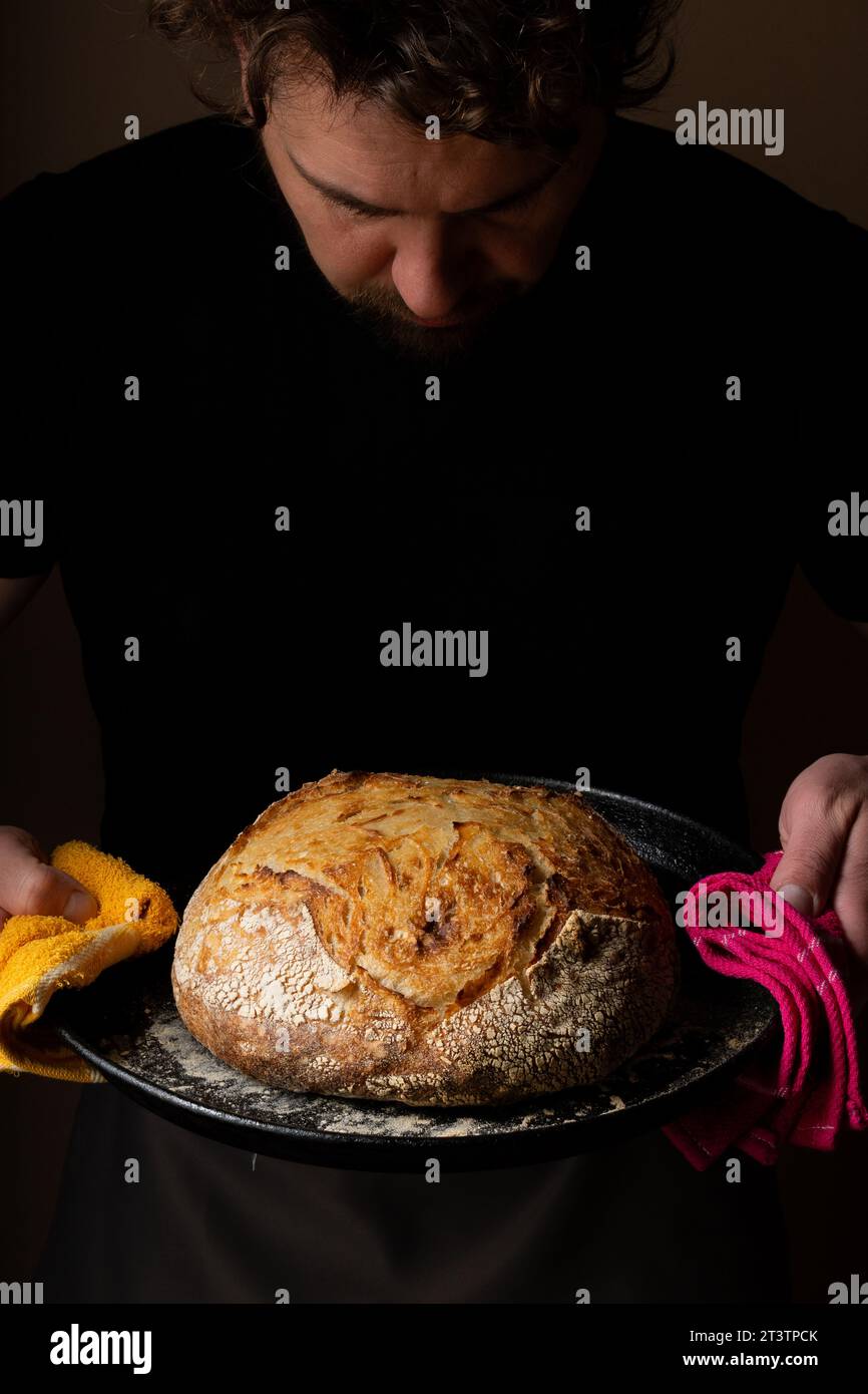 Attractive young Caucasian chef posing with white sourdough bread. The ...