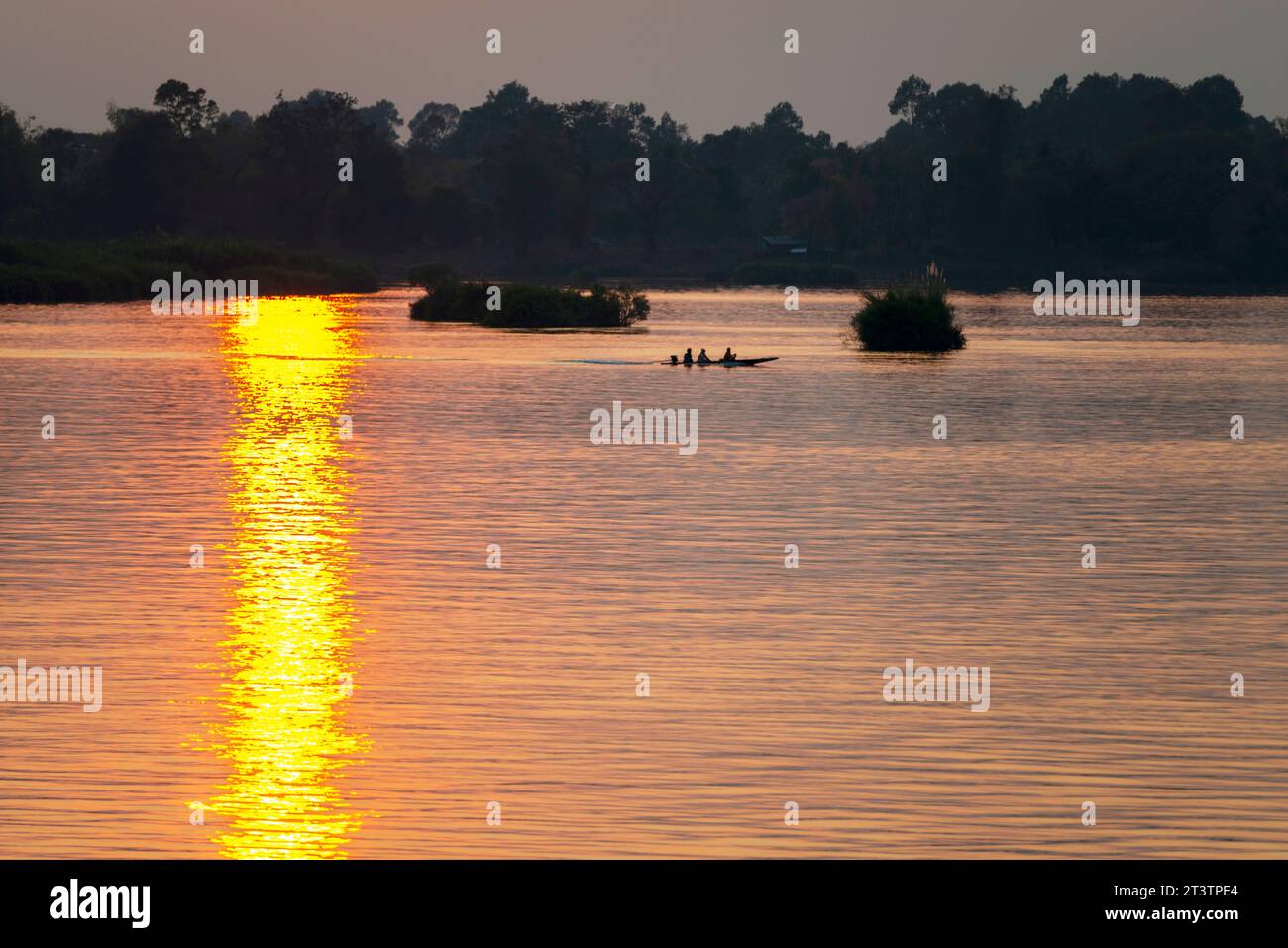 Silhouettes of human figures in a small canoe,drifting across the calm ...