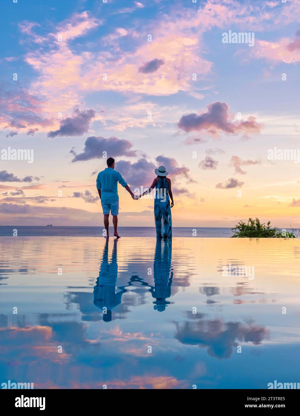 Young men and women watching the sunset with reflection in the infinity ...