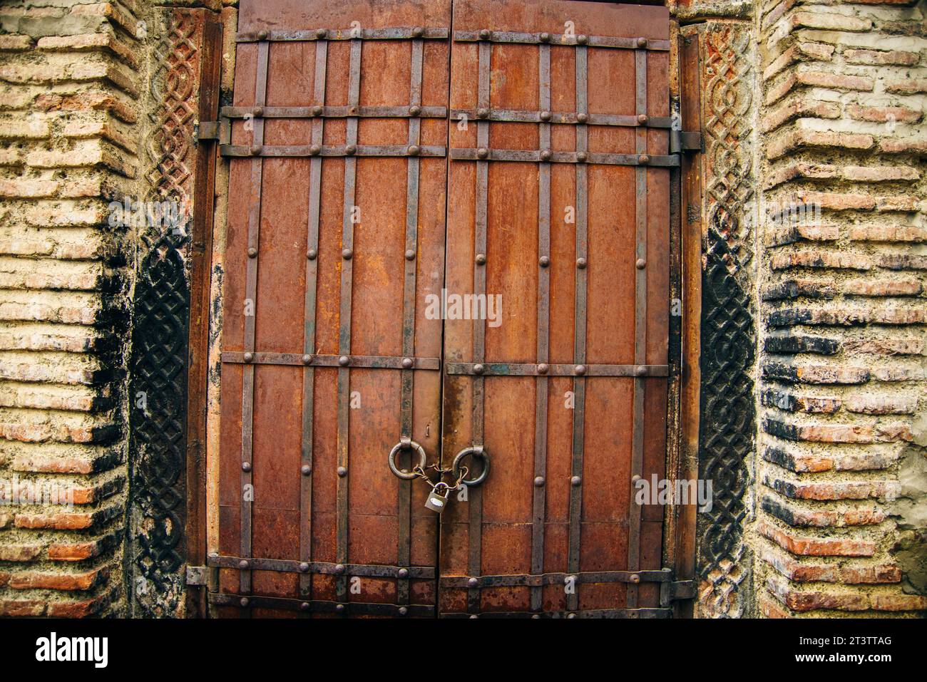 Close up of a heavy wooden plant double door, with iron hinges and ...