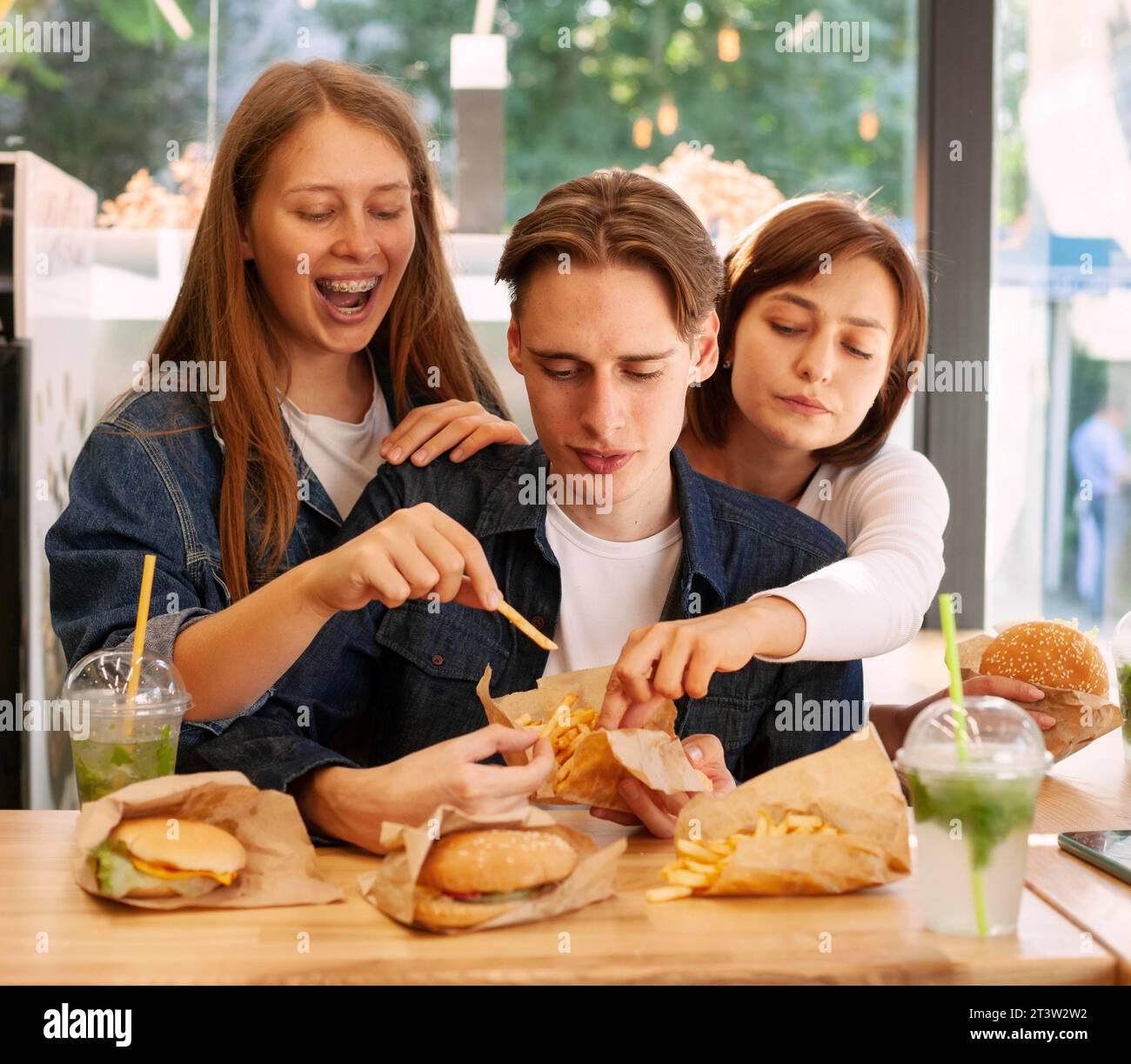 Group friends fast food restaurant eating burgers Stock Photo - Alamy