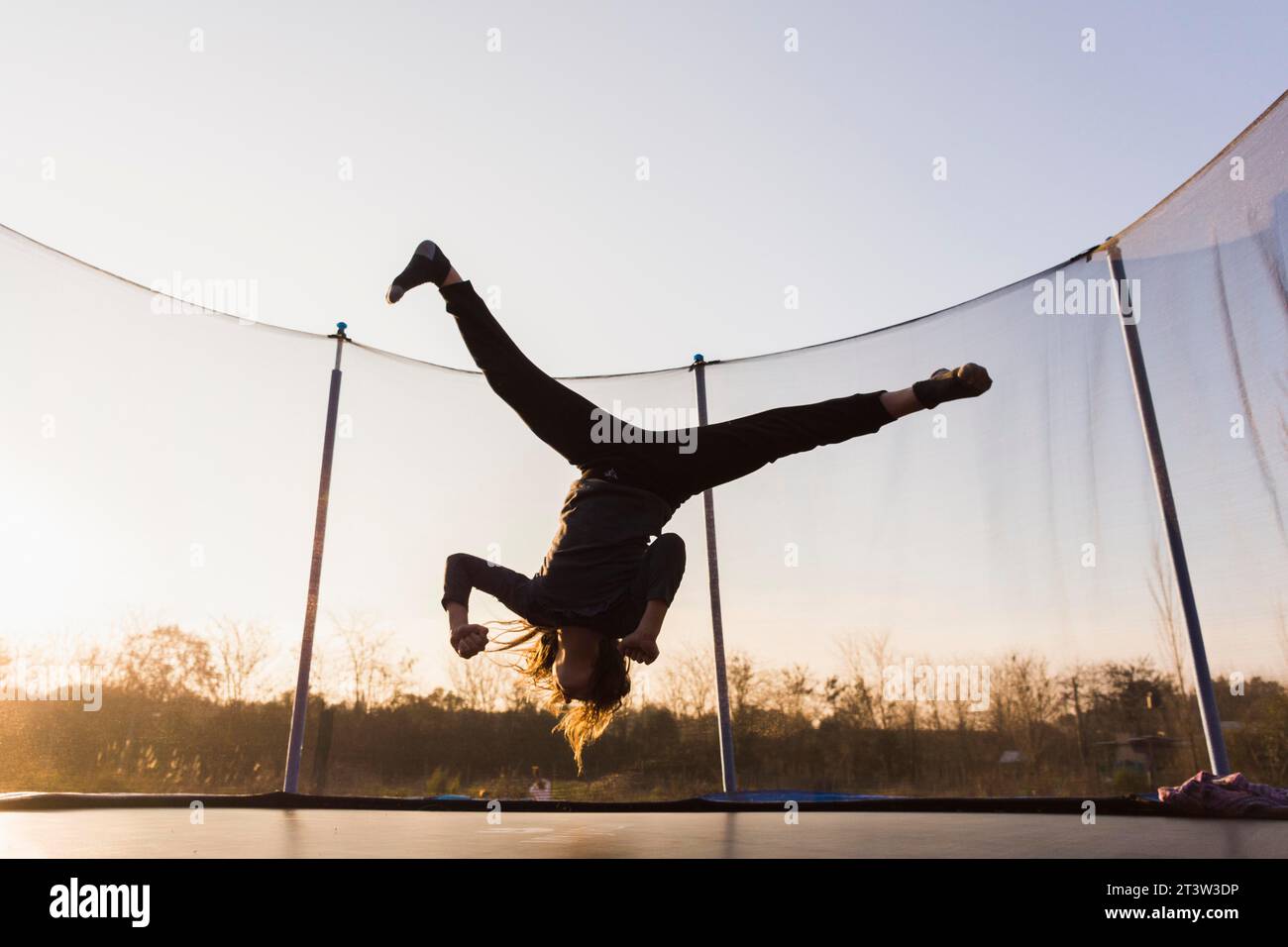 Silhouette girl jumping trampoline doing split Stock Photo - Alamy