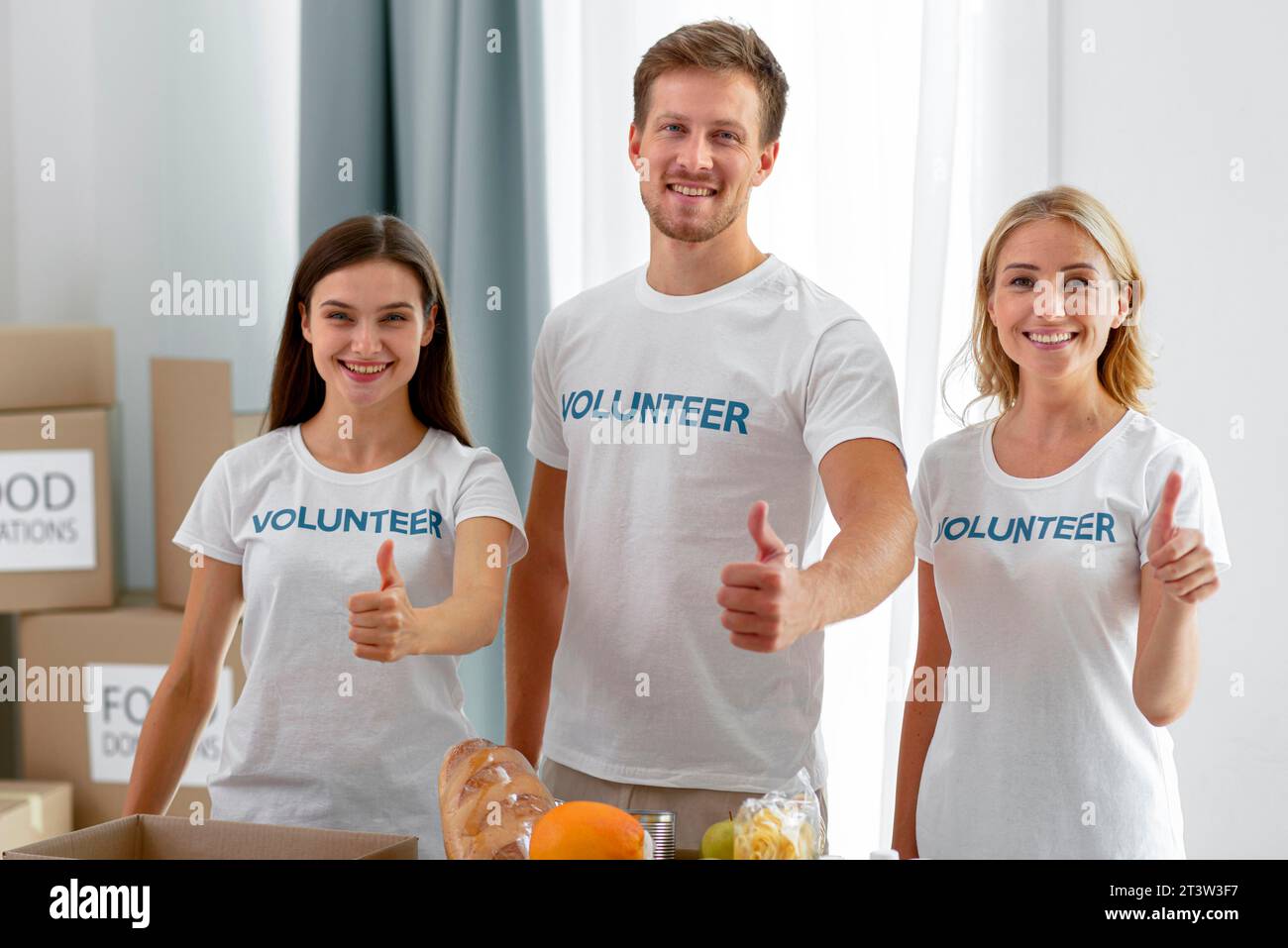 Smiley volunteers posing while giving thumbs up Stock Photo - Alamy
