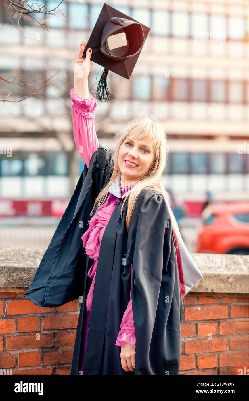 forty - year - old happy woman in graduation gown walking around city ...