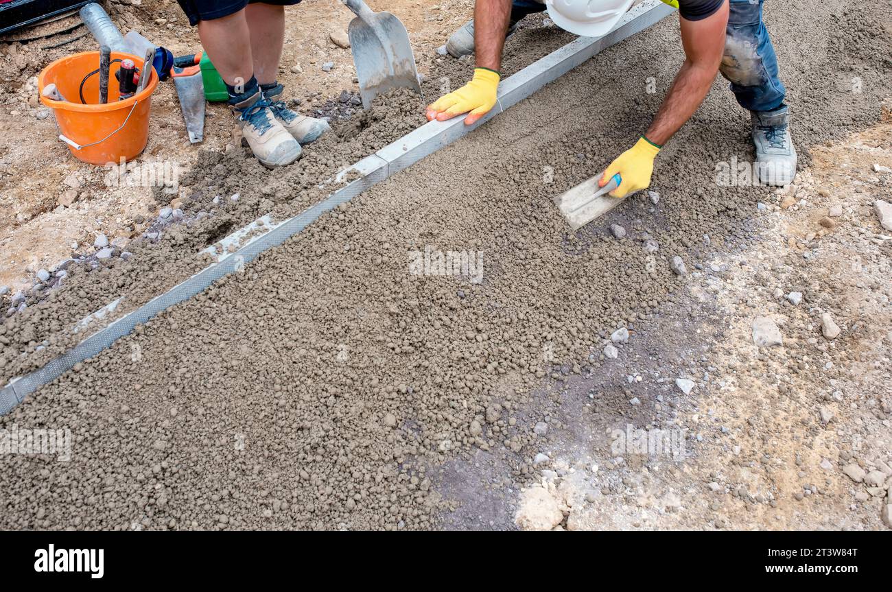 Builder placing edging kerbs on semi-dry concrete Stock Photo - Alamy