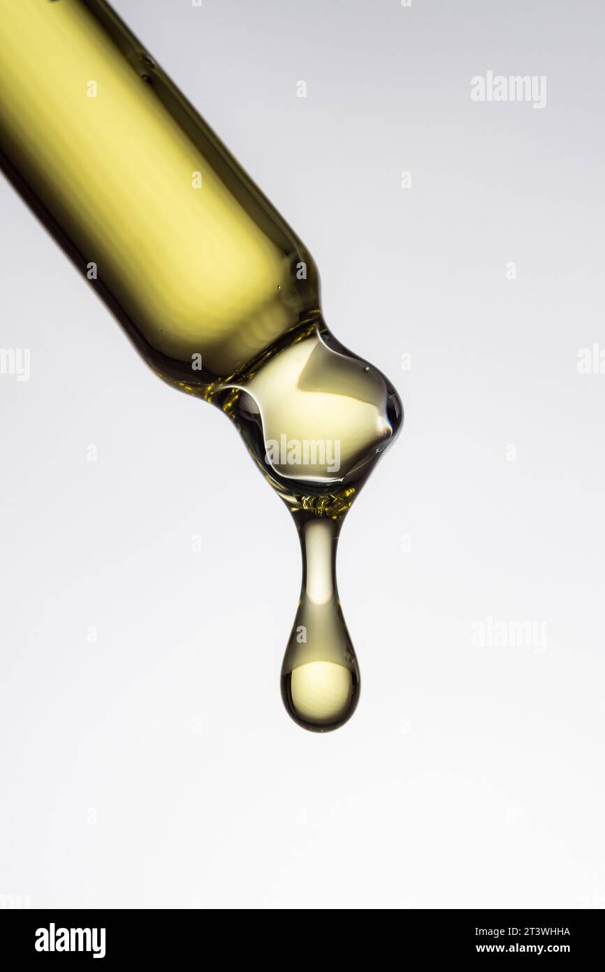 Dropper pipette with transparent yellow drops with bubbles on white ...