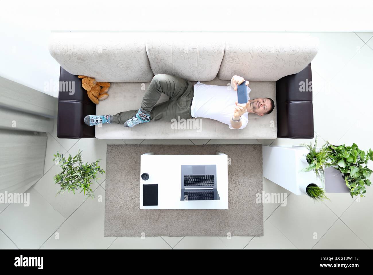 Man lie on sofa and hold modern smartphone in hand Stock Photo - Alamy