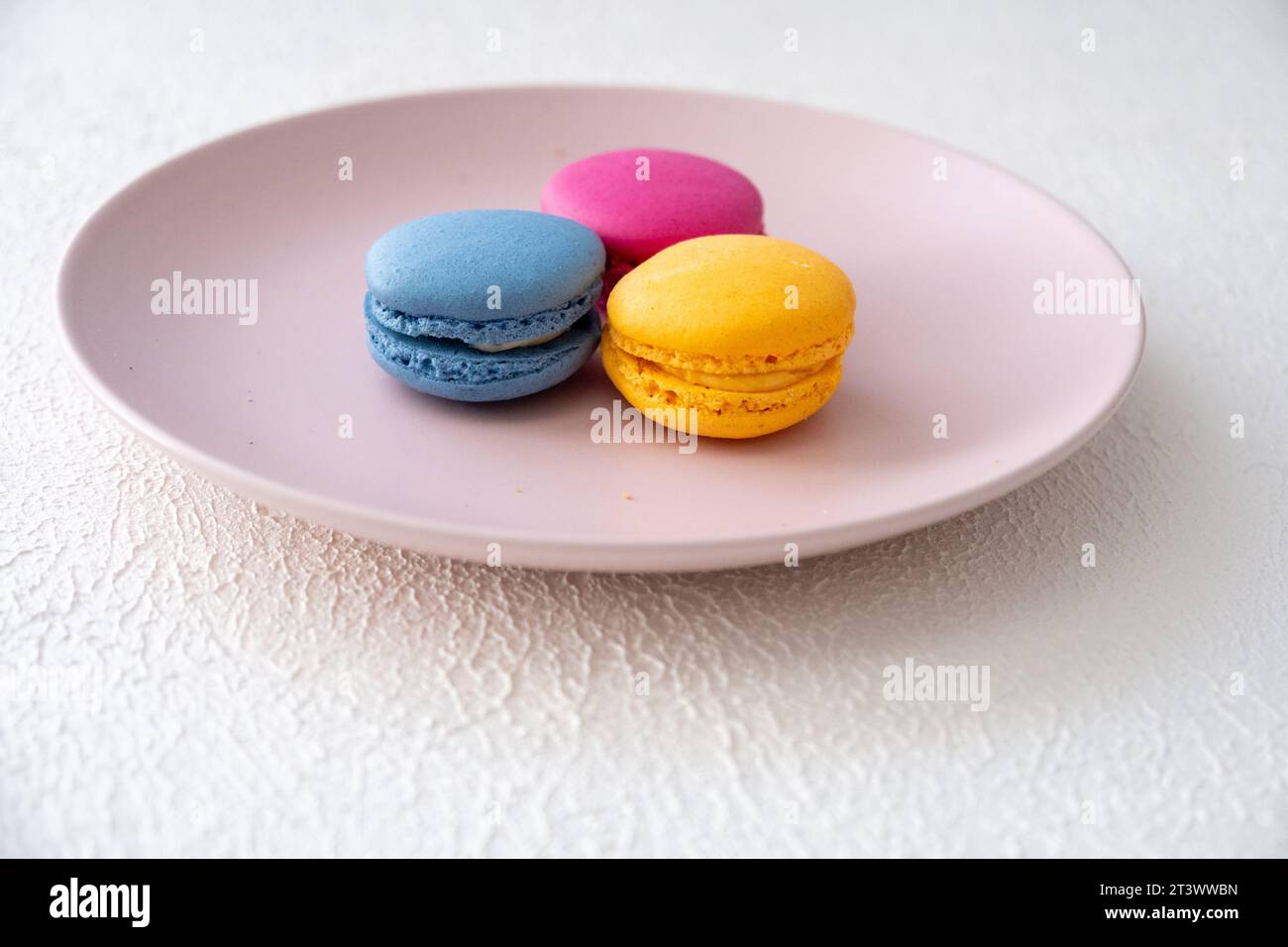 different colors macaroons and various chocolates on a white background ...