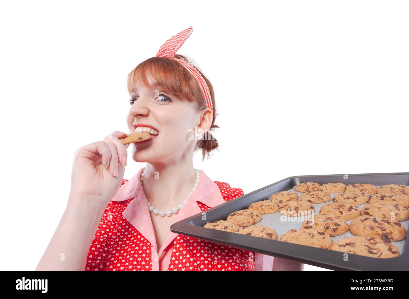 Happy vintage style housewife tasting her freshly baked homemade sweets ...