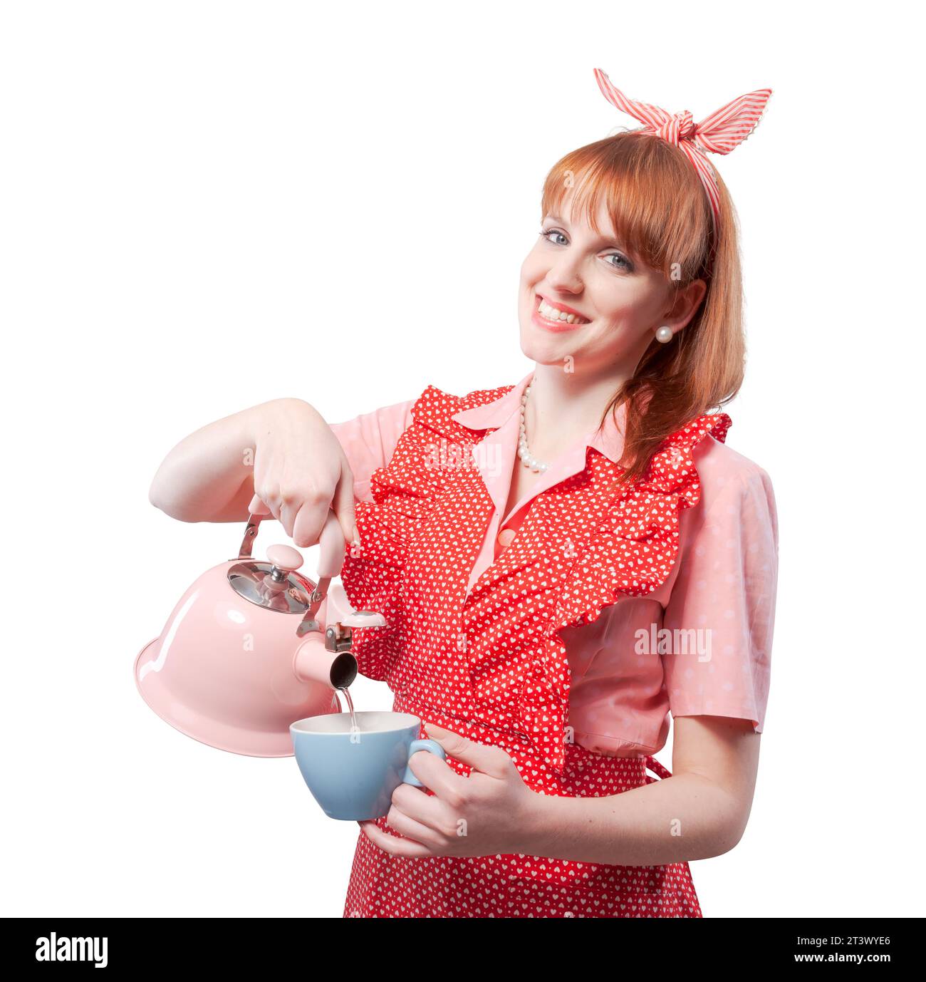 Cheerful beautiful traditional housewife pouring hot water in a cup and ...