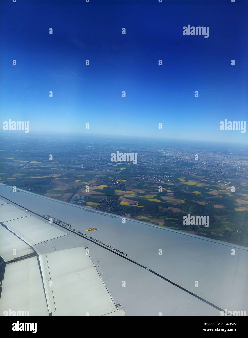 Airplane wing and land far under the plane. Flight in the deep blue sky ...