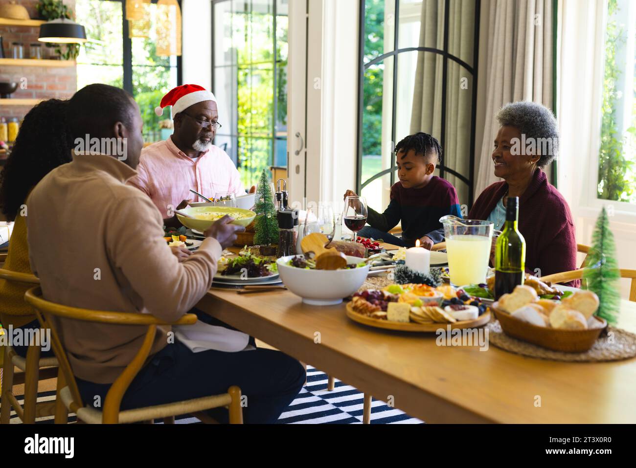 Happy african american family having christmas dinner in decorated ...
