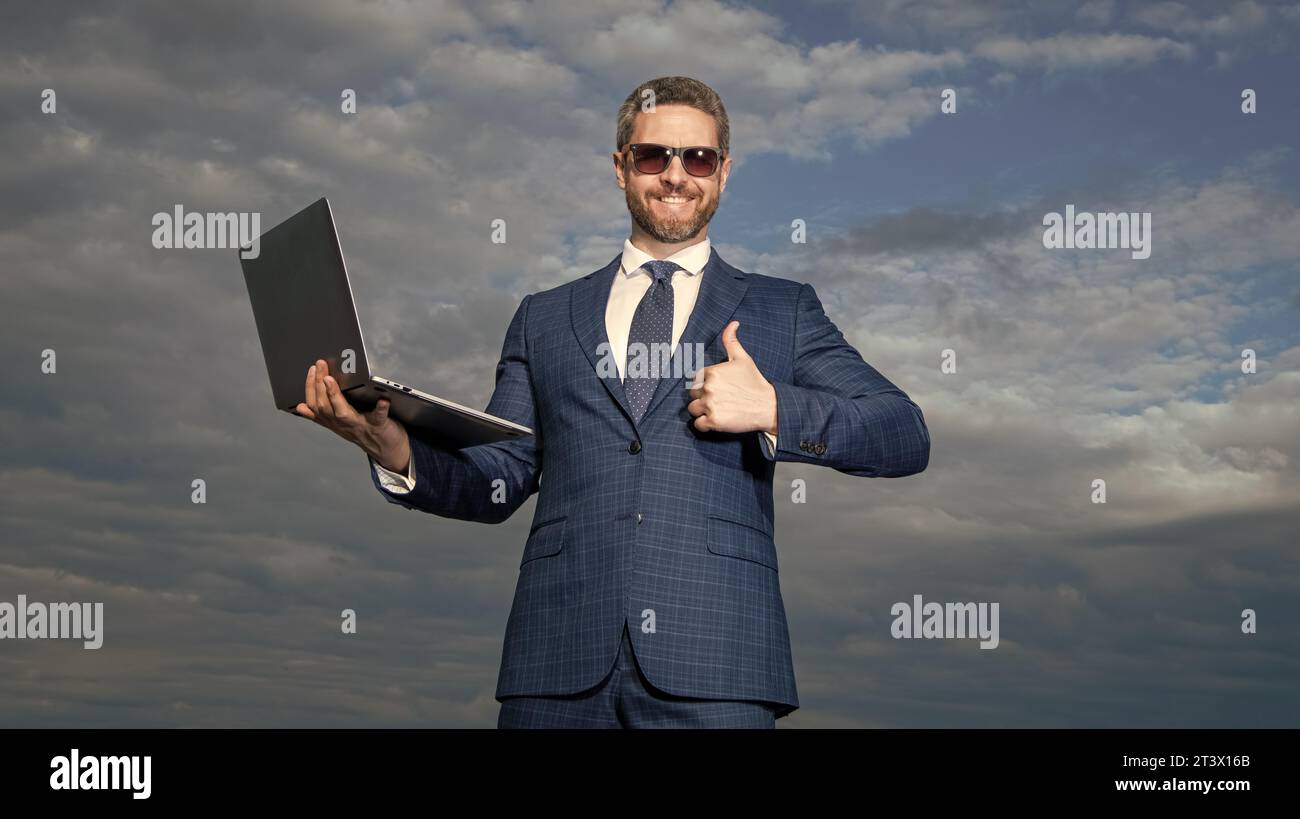 Happy programmer holding laptop. Computer programmer showing thumb gesture. Hardware programmer ...
