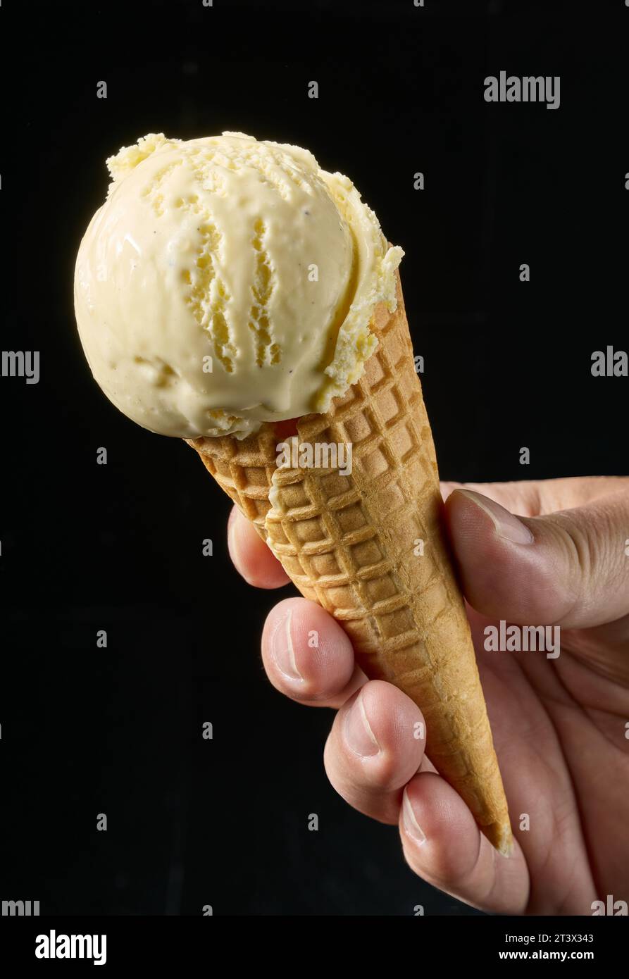 close up of vanilla ice cream in waffle cone in human hand isolated on ...