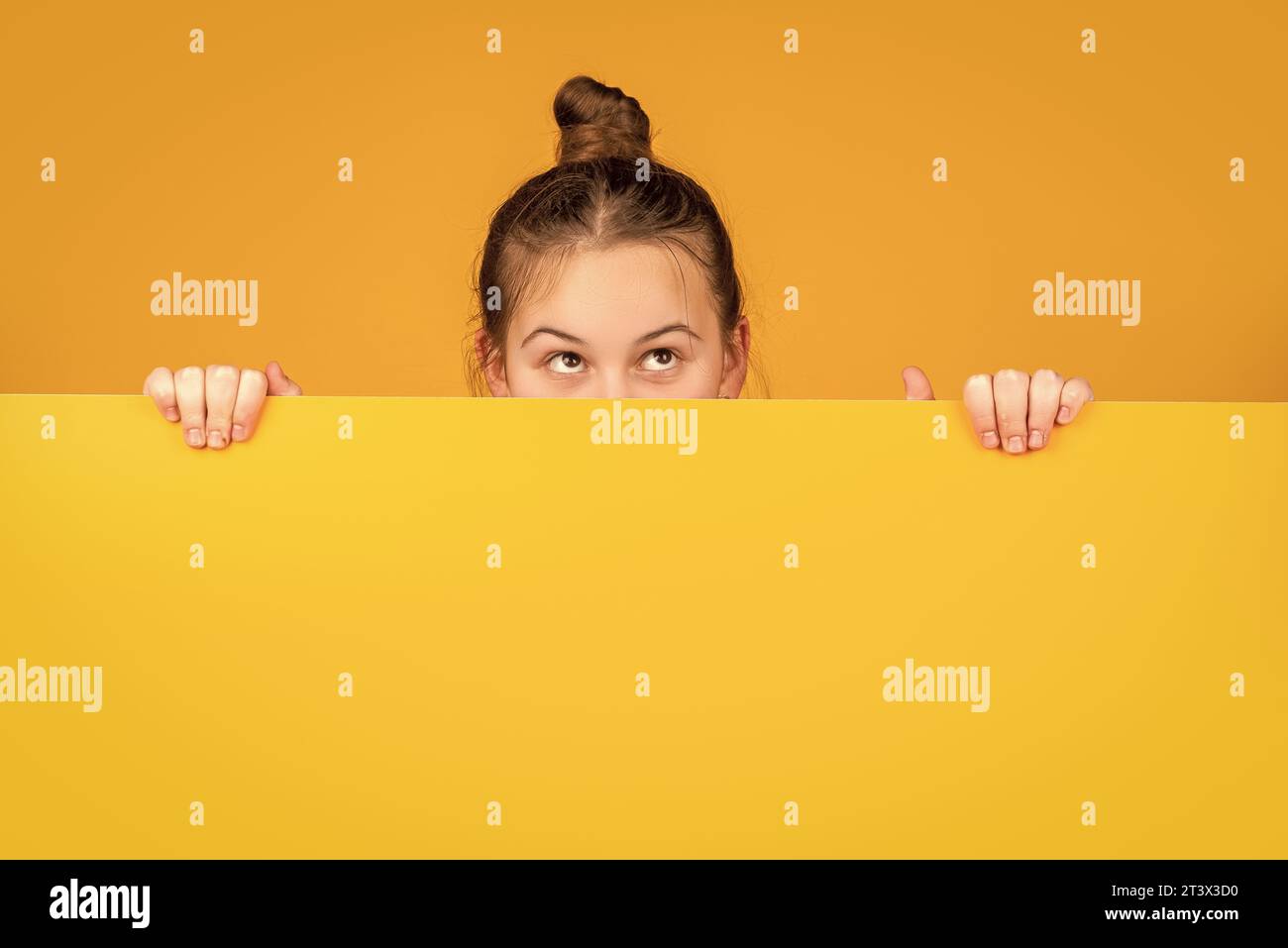 girl hiding behind yellow paper with copy space for advertisement Stock ...
