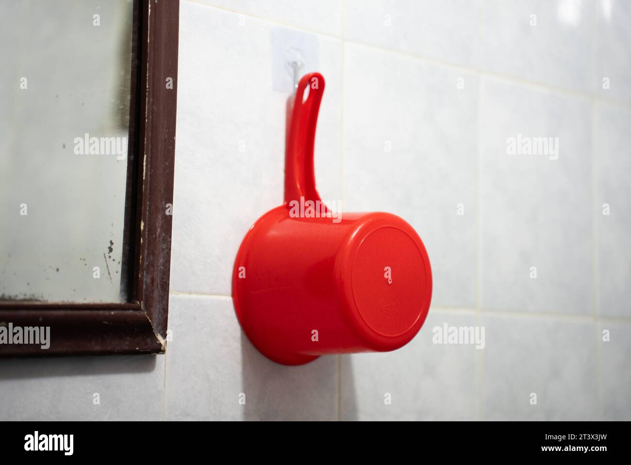 Indonesian gayung or water sadle hanged on the wall next to the old ...