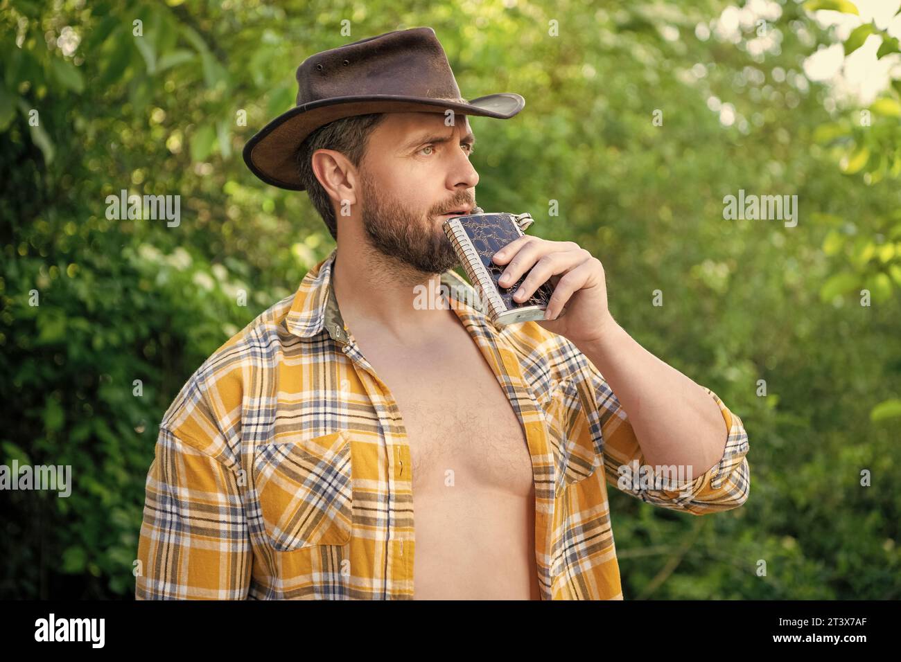 masculine cowboy drink from flask wear hat. photo of masculine cowboy ...