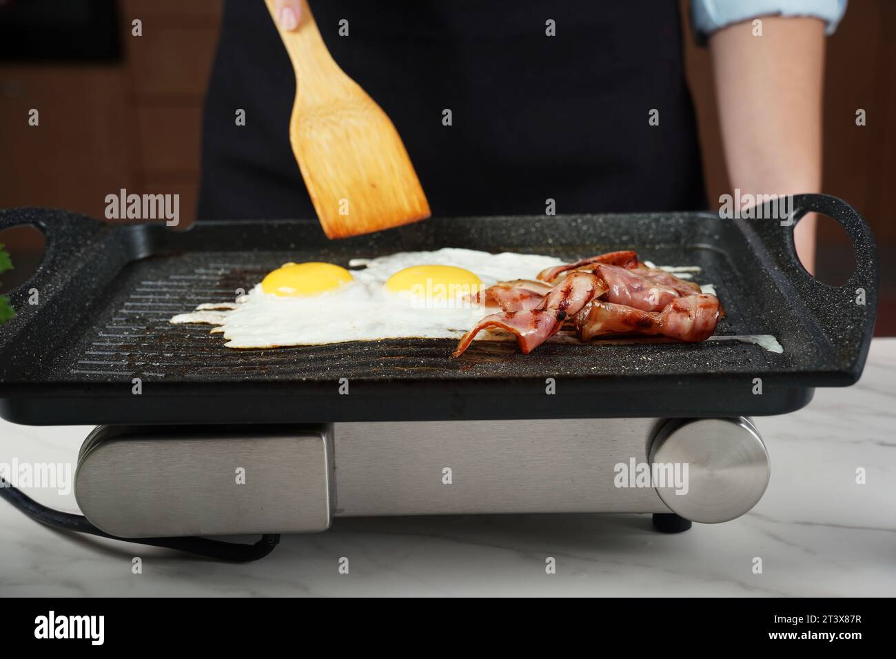 Woman is preparing eggs and bacon in frying pan Stock Photo - Alamy