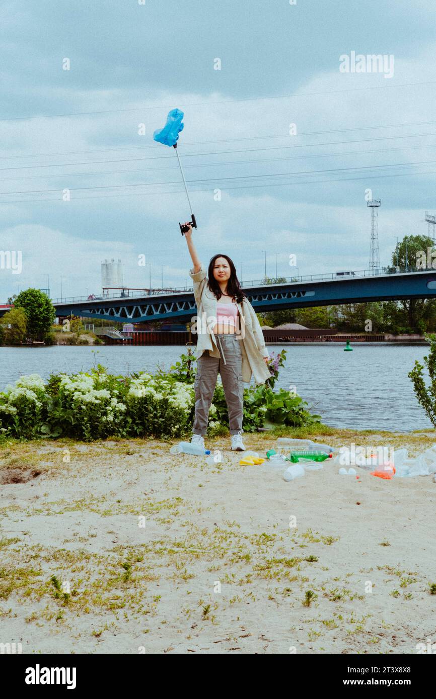 Full length portrait of confident young woman picking garbage near ...