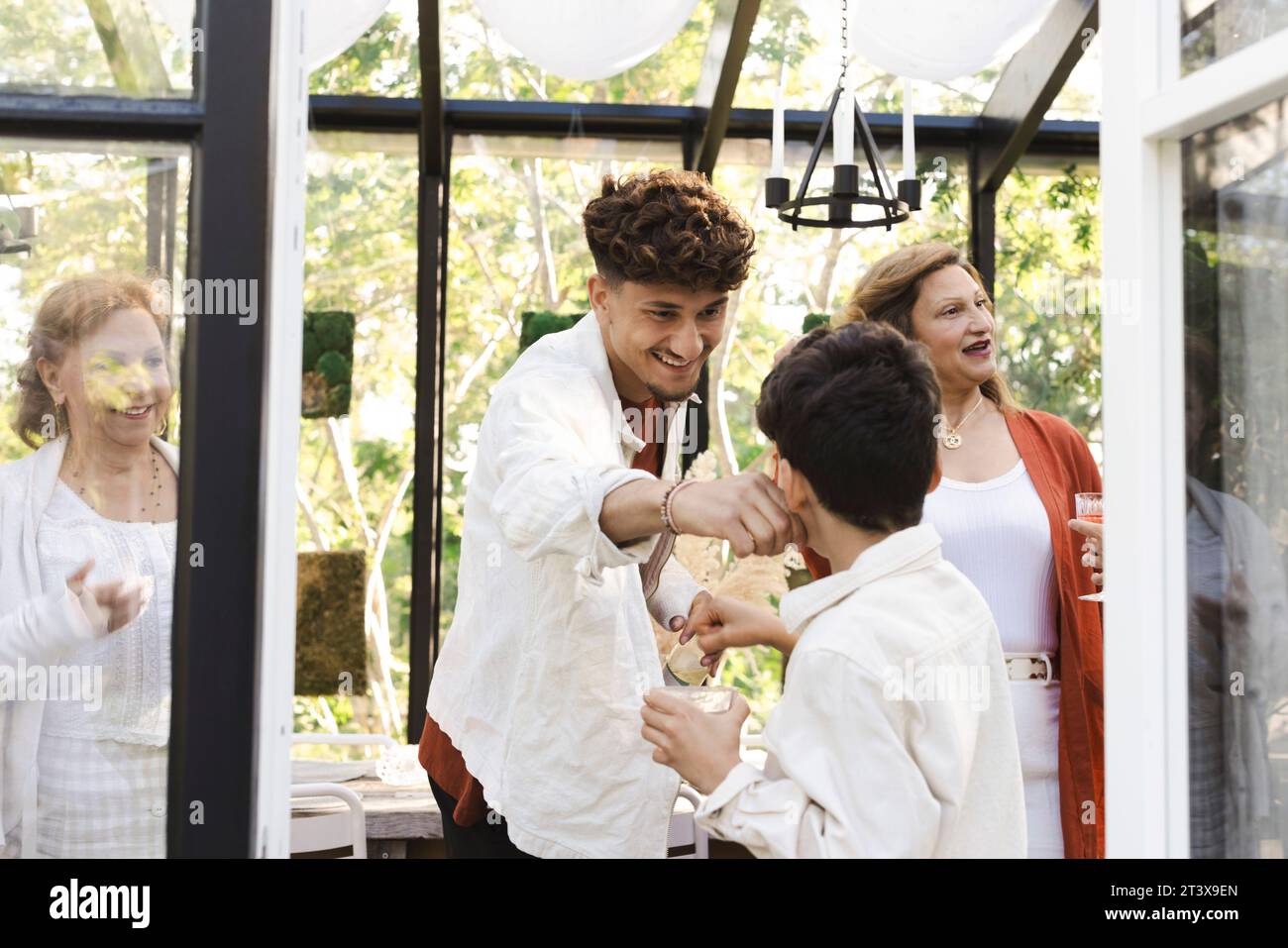 Smiling young man pinching boy's cheek during midsummer party at back ...