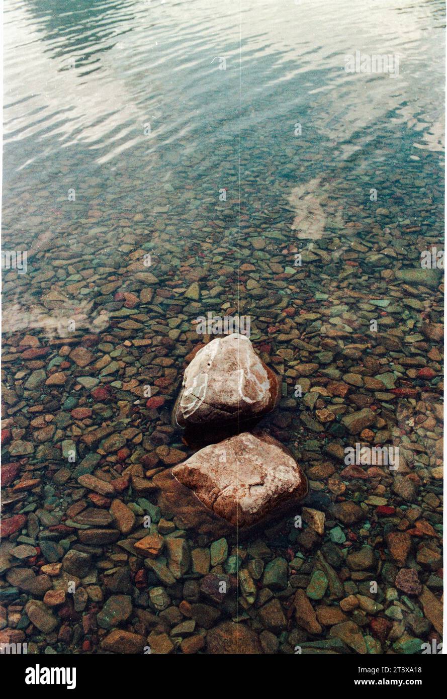 Colorful rocks shine brightly in clear blue lake water Stock Photo - Alamy