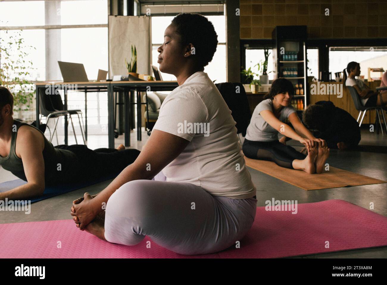 Full length side view of businesswoman practicing butterfly pose on mat ...