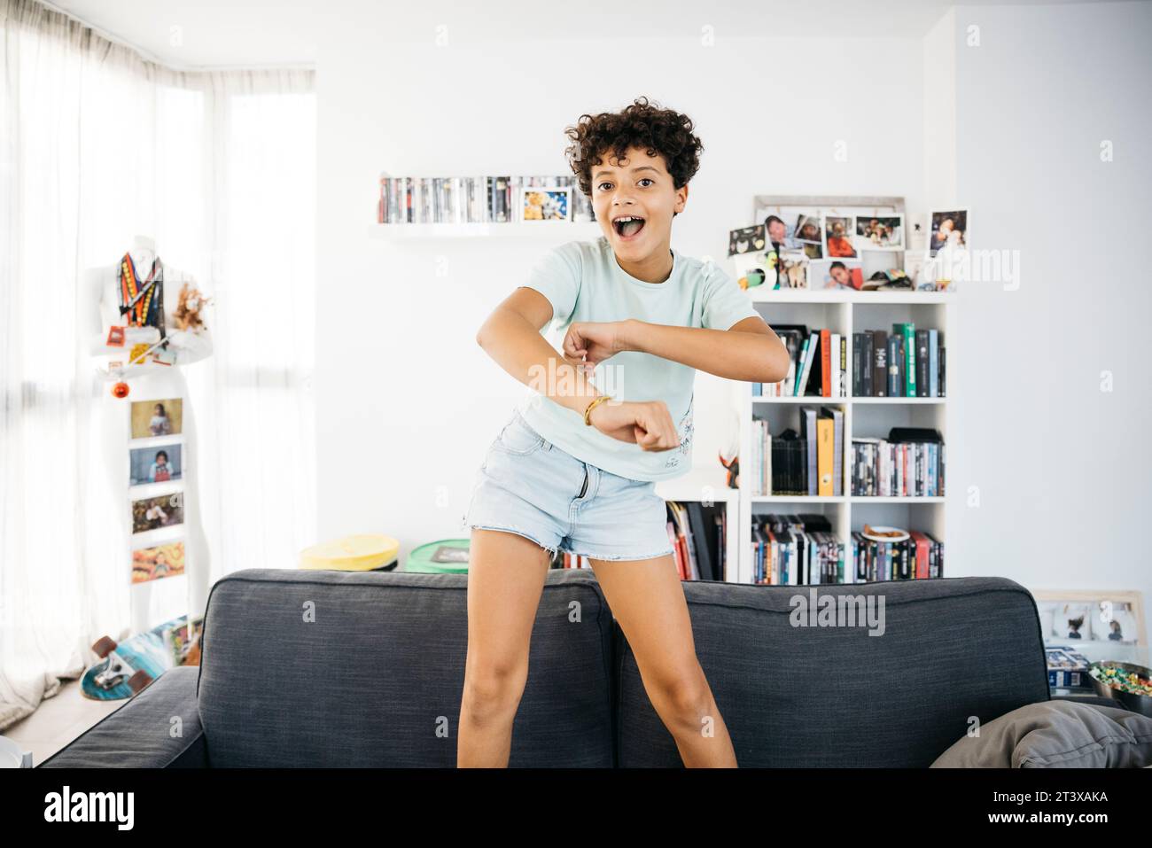 Happy ten years old girl dancing on a sofa in a living room. Girl ...