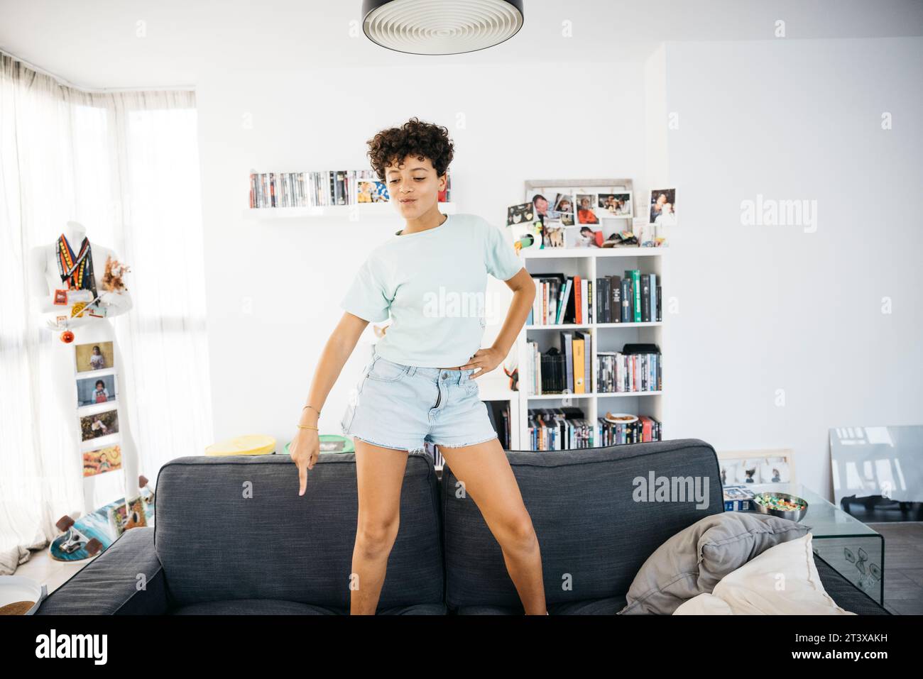 Happy ten years old girl dancing on a sofa in a living room. Girl ...
