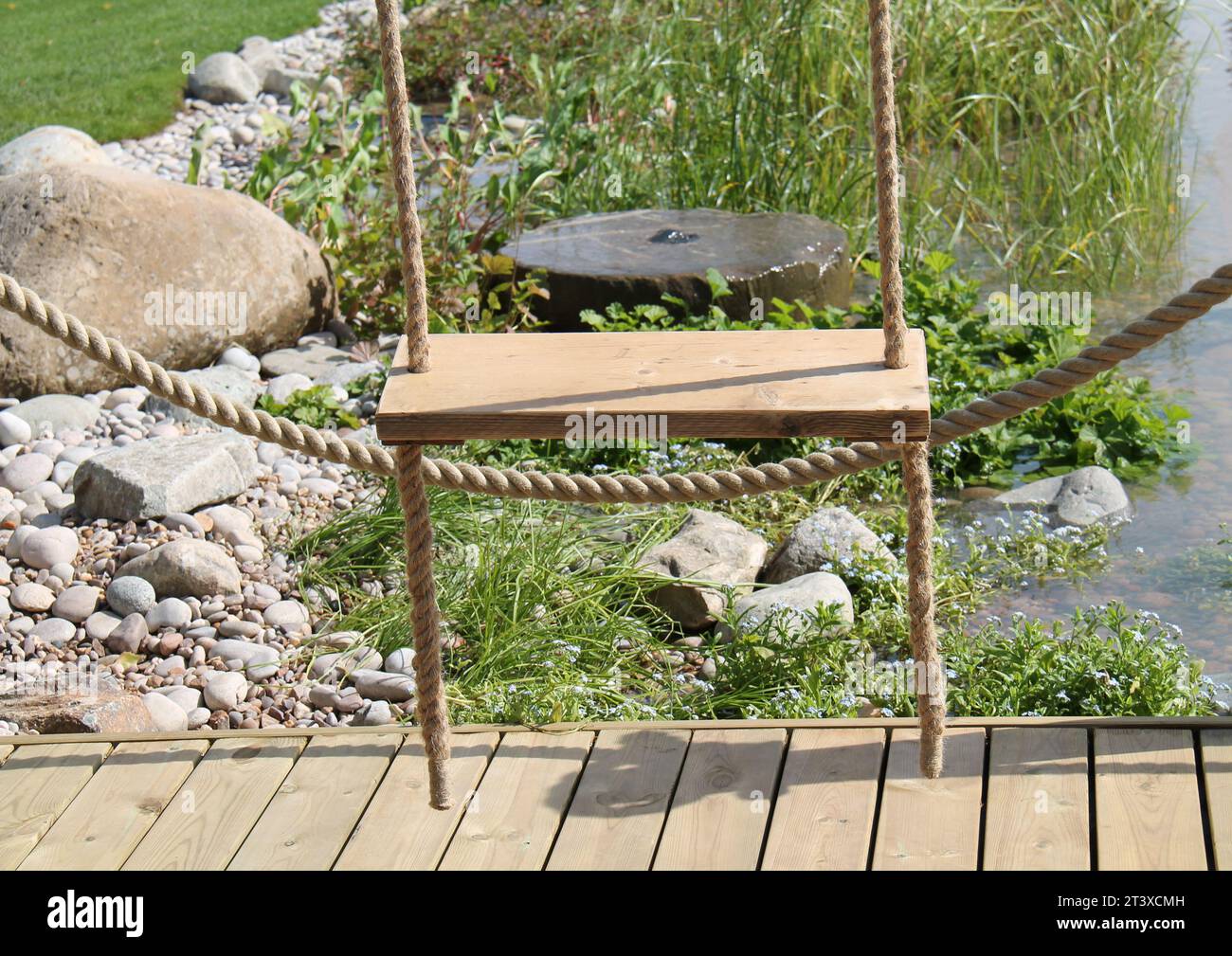 A Wooden Garden Rope Swing Next to a Pond Stock Photo - Alamy
