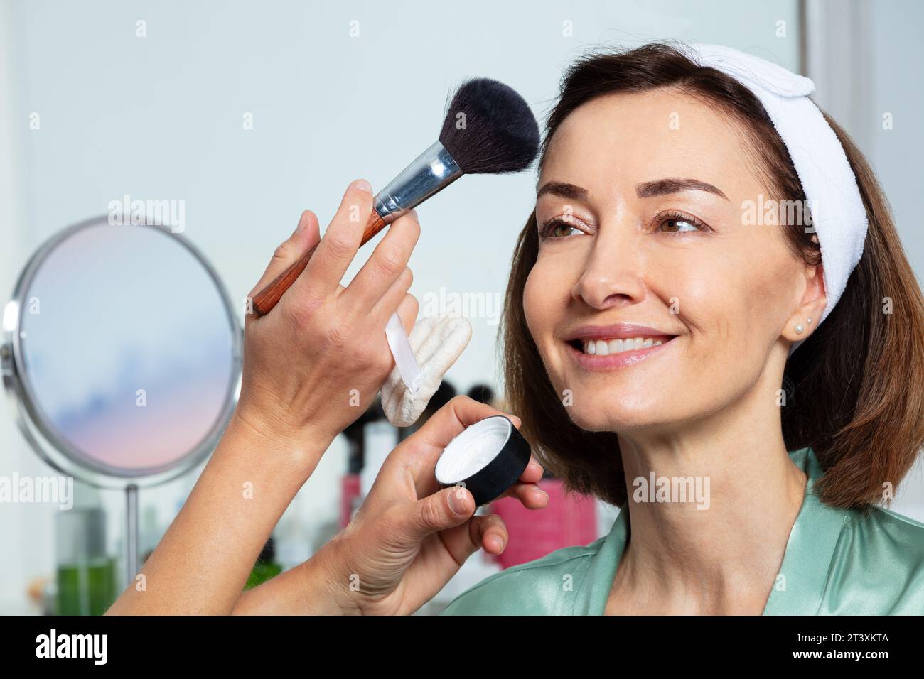 Beautician applies makeup on smiling middle-aged model Stock Photo - Alamy