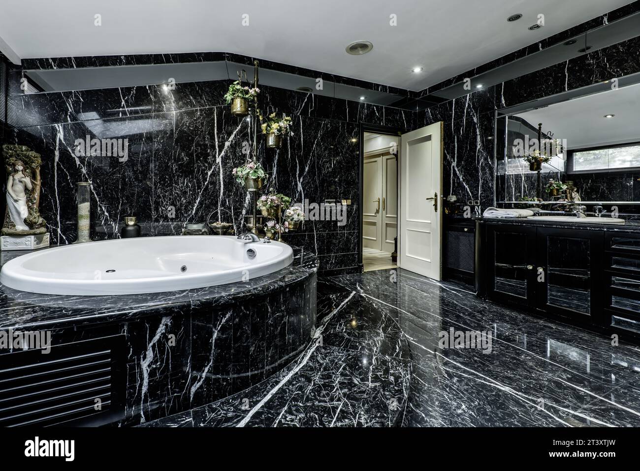 large bathroom tiled with black marble with black veins, circular ...